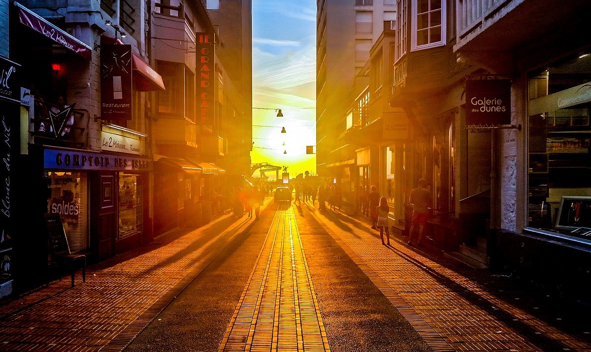 a walking street of shops glowing in the sun at sunset or sunrise ...