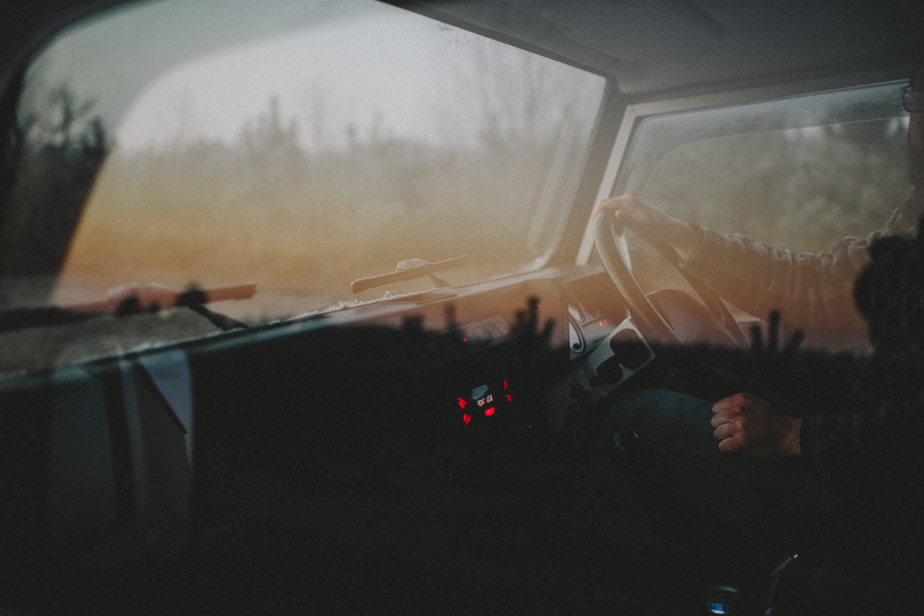 looking into dashboard of car with driver and steering wheel window ...