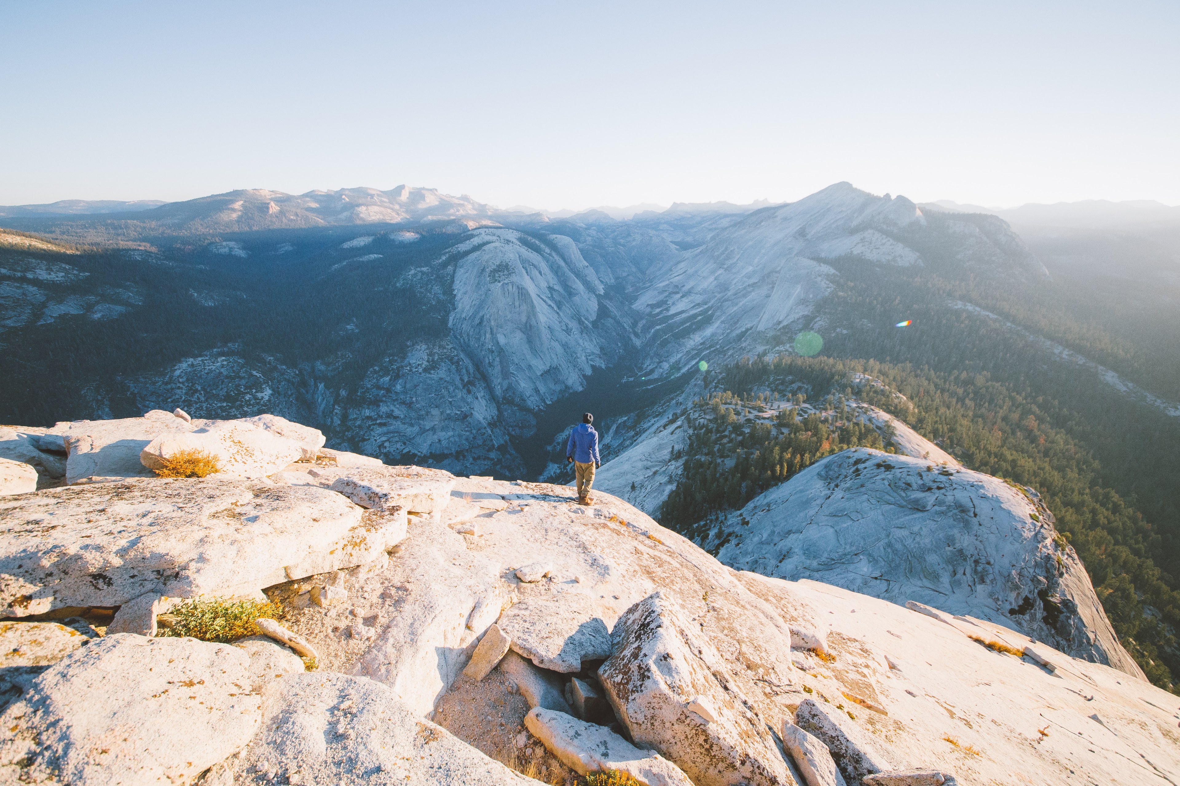 a man with a backpack standing on a ledge overlooking a vast misty ...