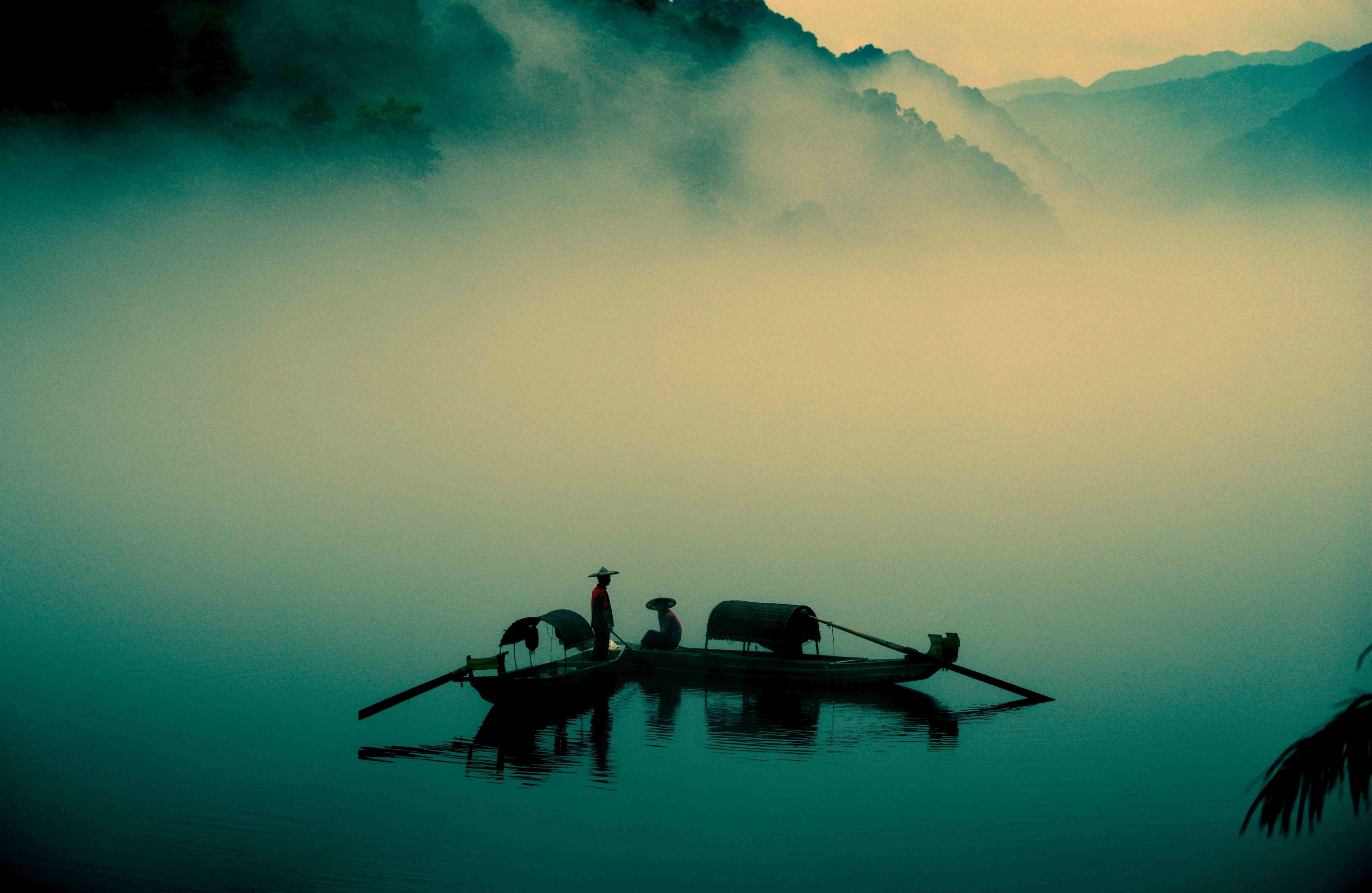 two fisherman wearing hats on their canoes on a lake in the morning fog ...