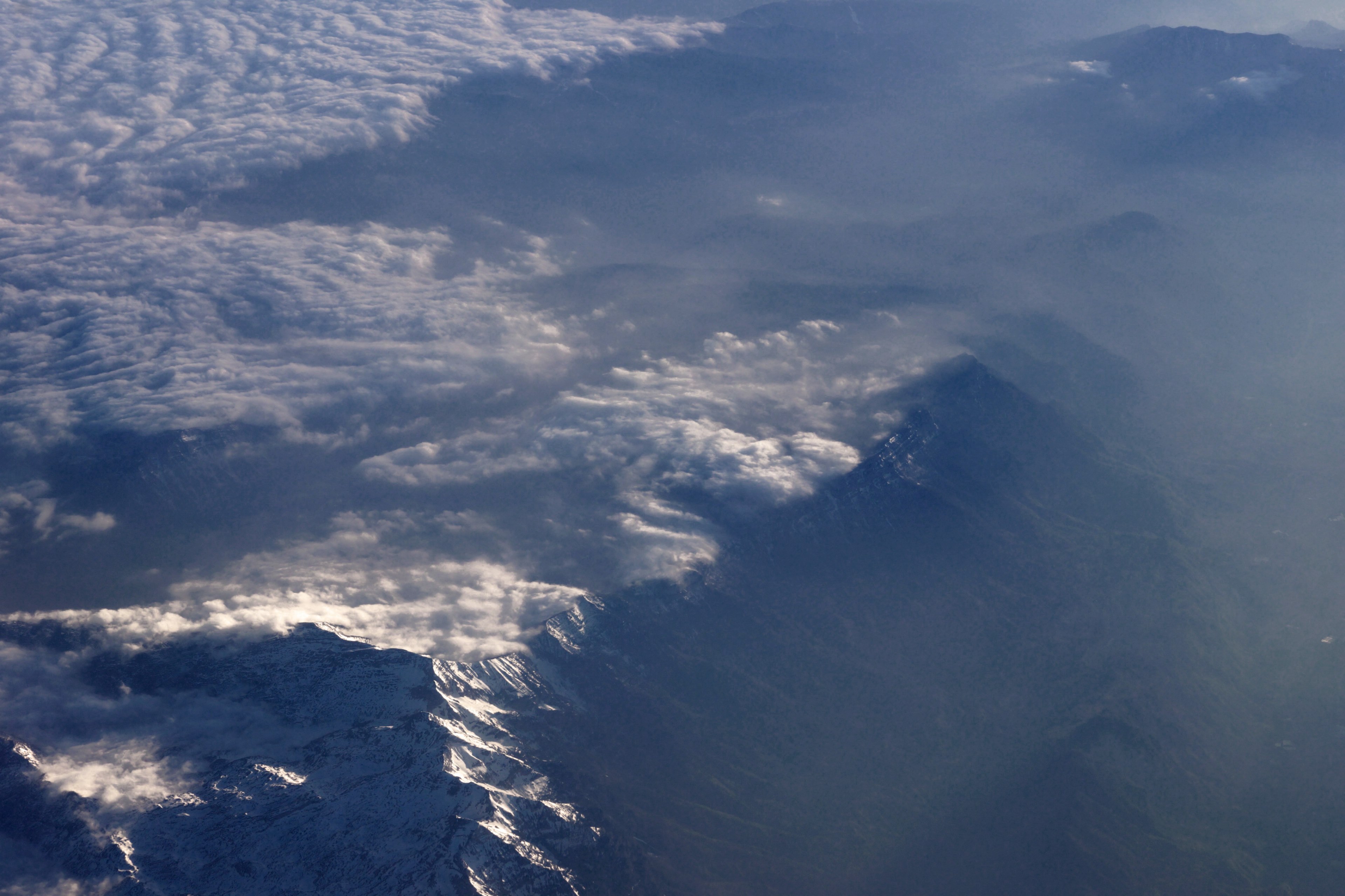 aerial view of the peaks of a mountain range and clouds from above ...