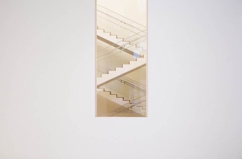 long shot of zig zag staircase through window in white wall the museum ...